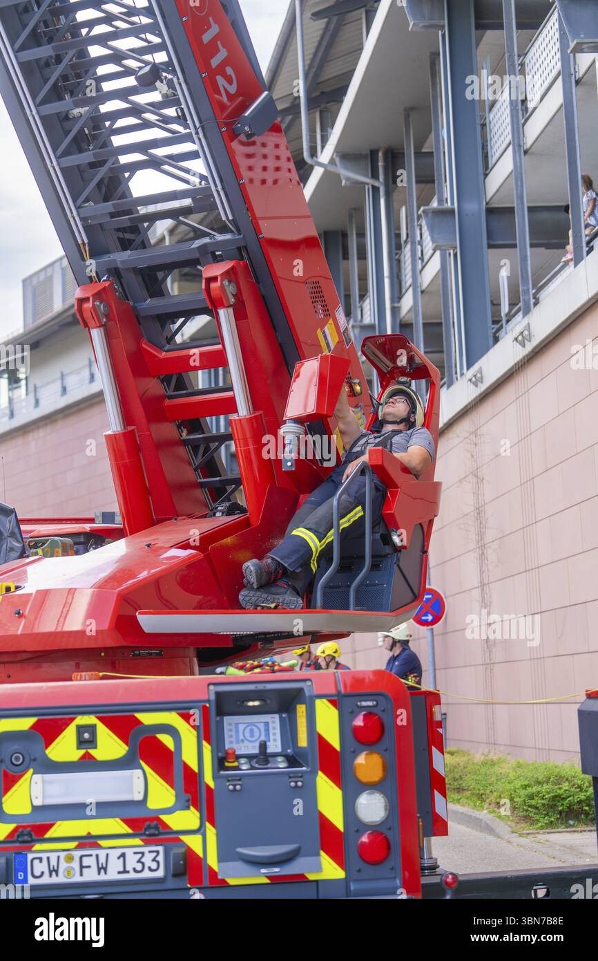 Firefighter resting on an extended lifting platform next to a building ...