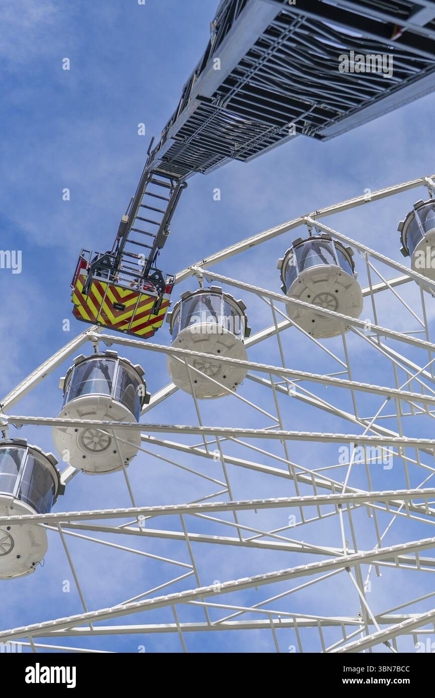 Fire brigade ladder reaches up to the Ferris wheel, ready for an ...