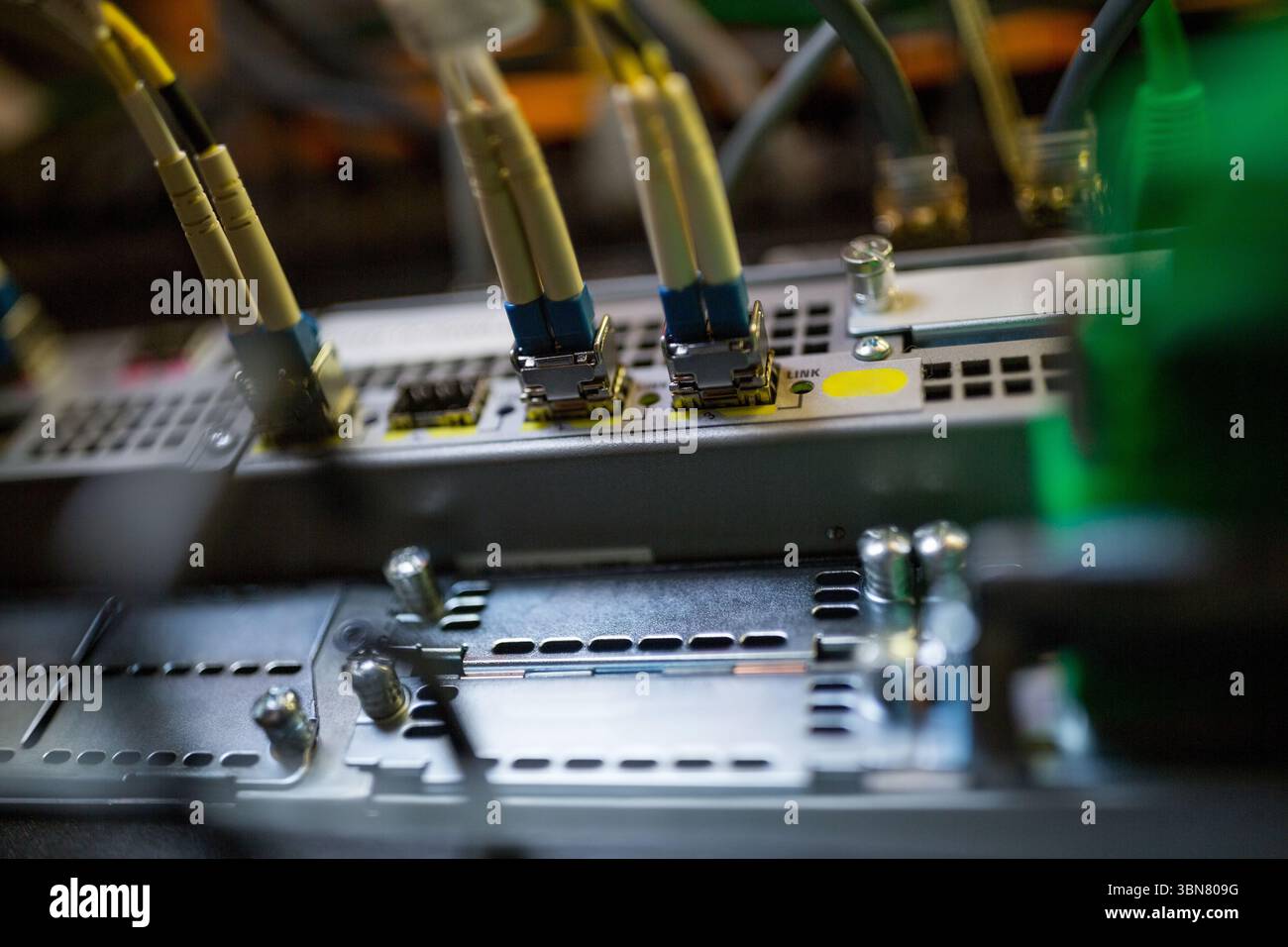 Flat design is showing LC fiber optic cables connecting into network patch panel chassis in rack ...