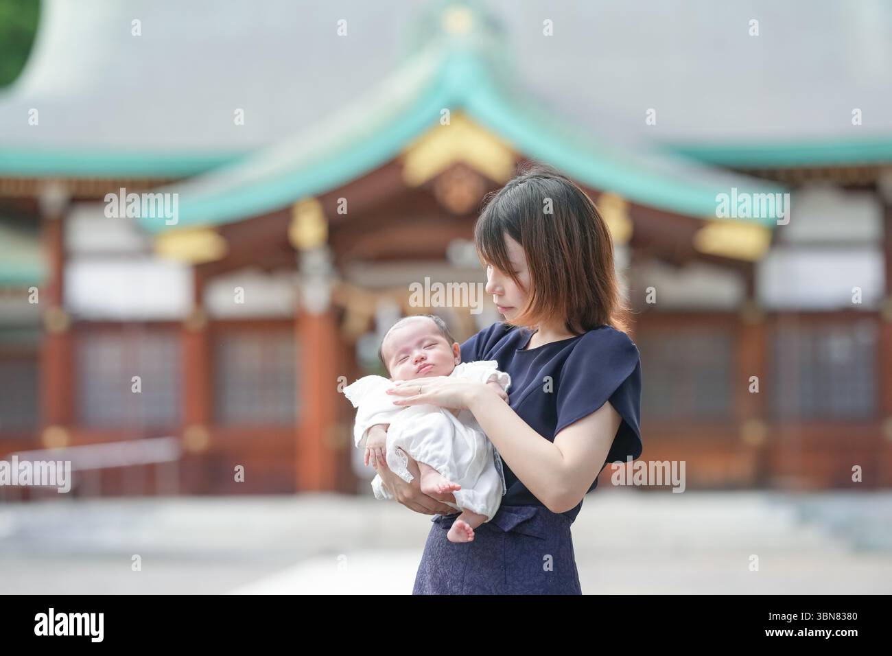 In June 2025, a young Japanese mother in her early twenties gently holds her one-month-old baby ...