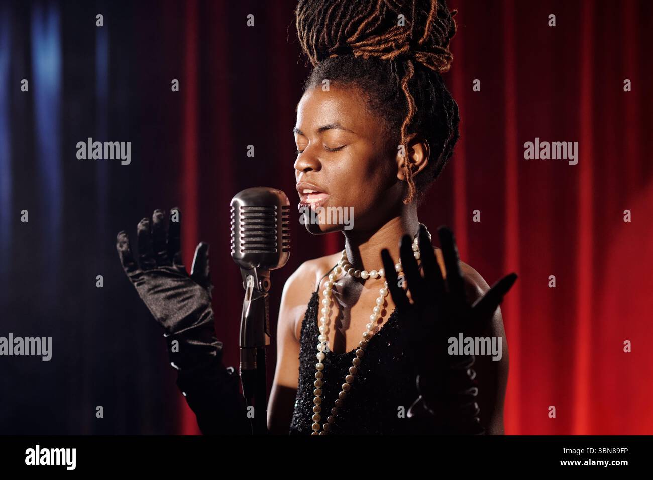 African American young adult woman singing into vintage microphone with ...