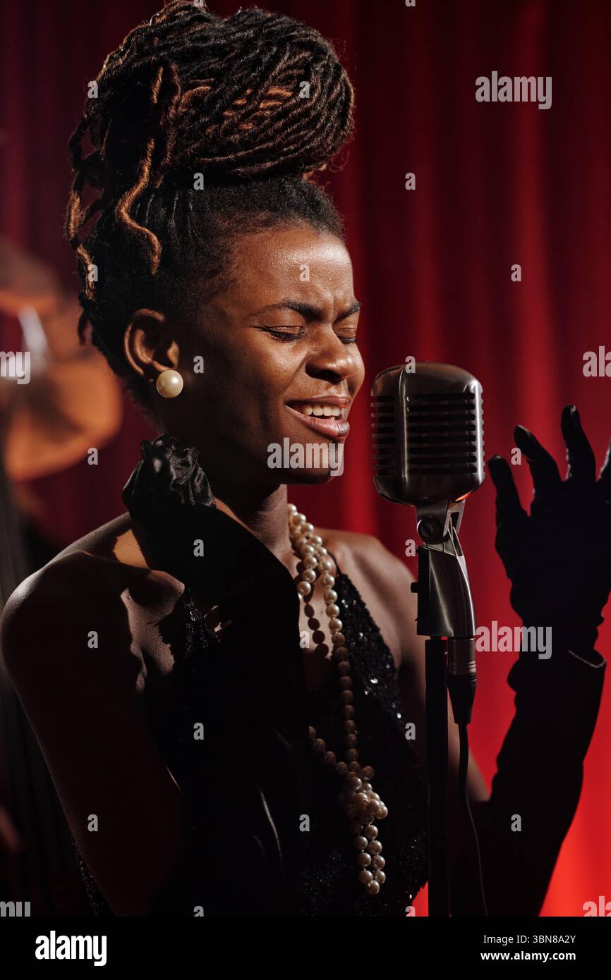 Black young adult woman singing passionately into vintage microphone on ...