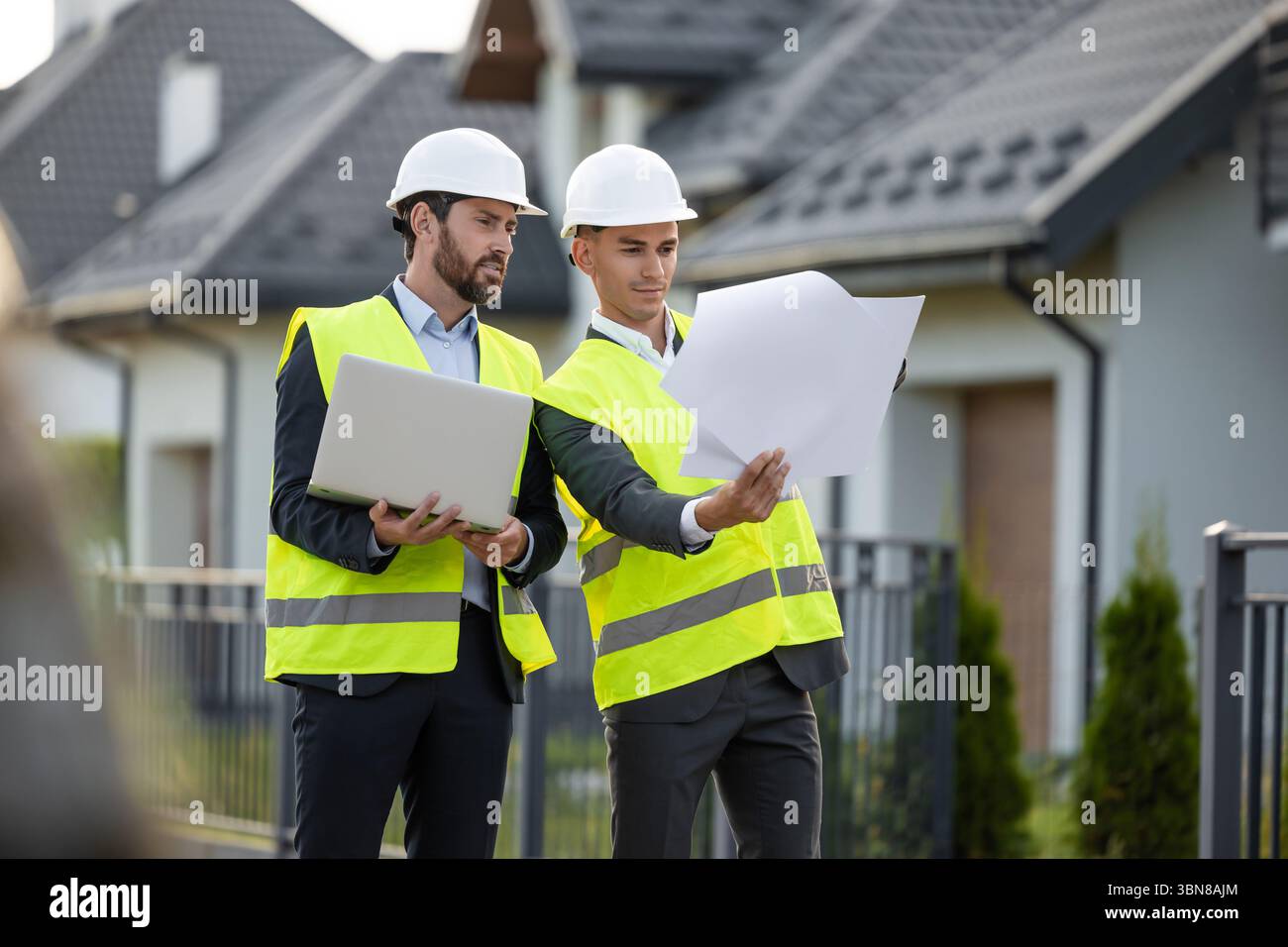 Construction workers reviewing plans in residential area Stock Photo ...