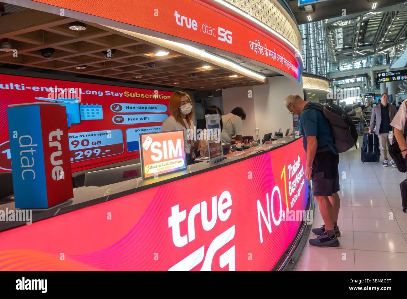 Tourist shopping True 5G mobile operator sim card kiosk at arrivals ...