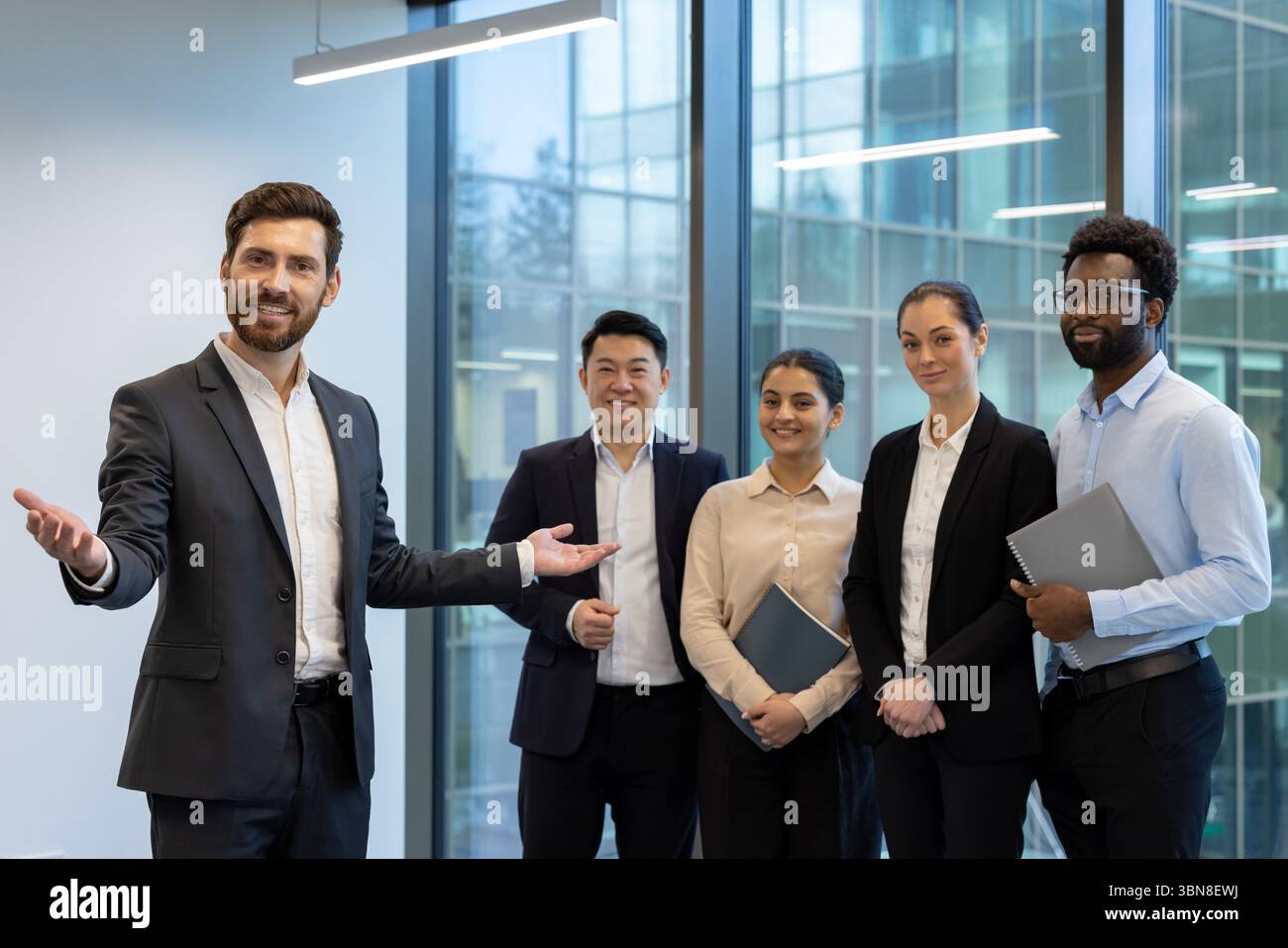 A diverse business team stands together in a modern office setting ...