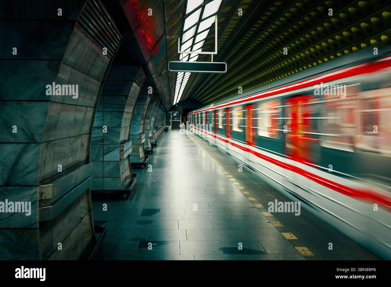 A modern metro train, blurred with motion as it passes an empty ...