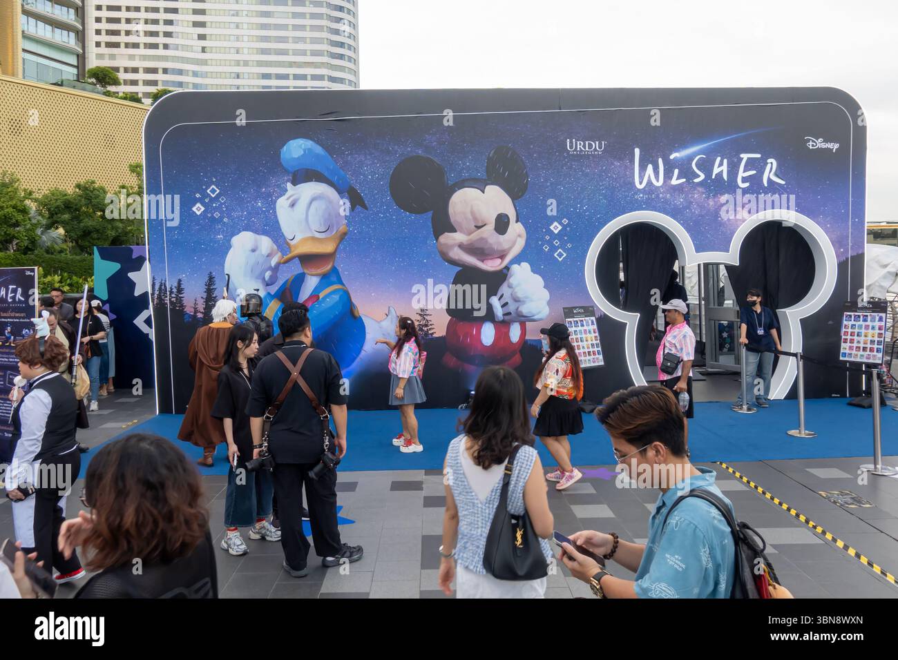A crowd at a Disney "Wisher" stand with Mickey Mouse and Donald Duck ...