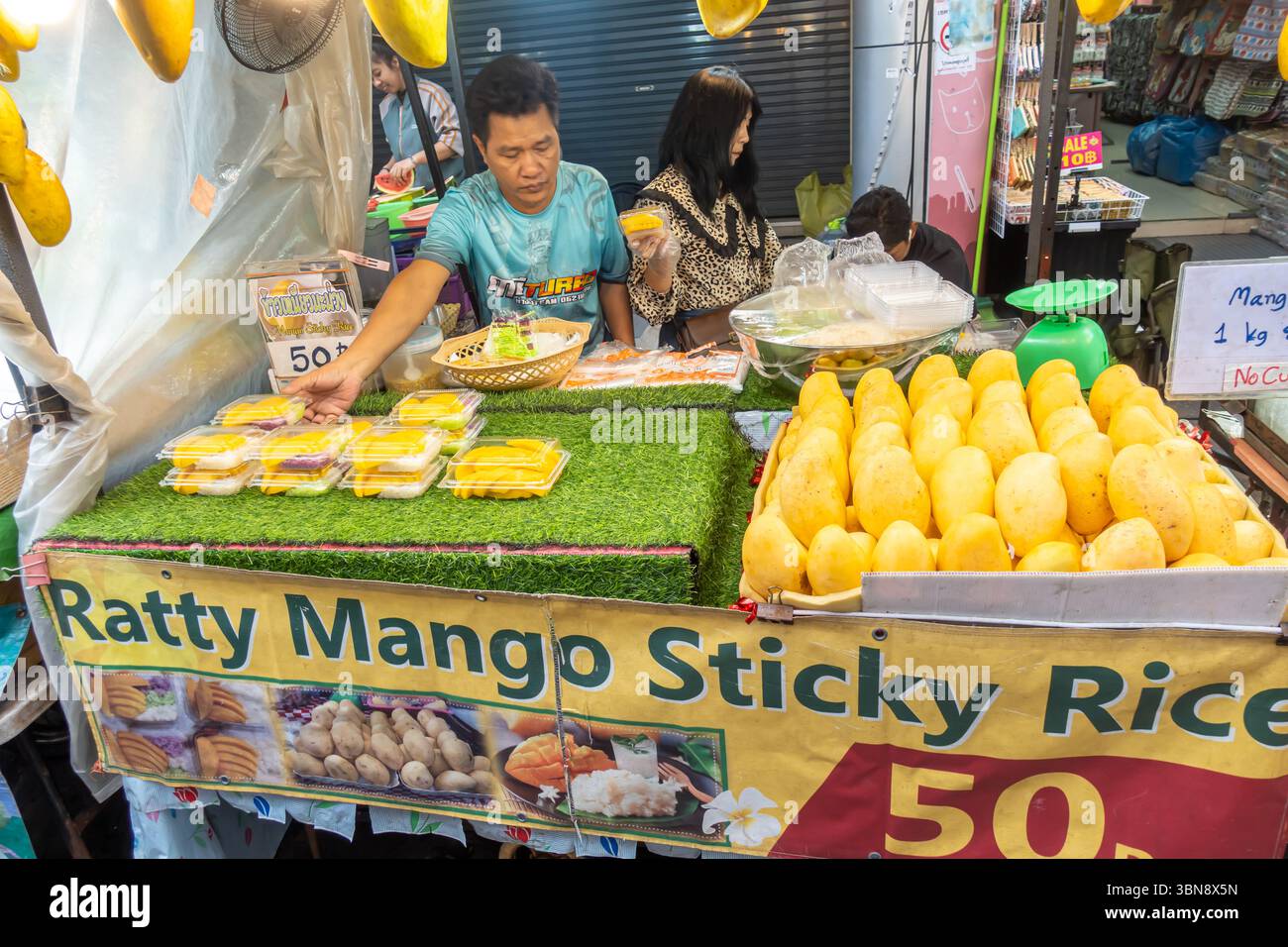 A vendor sells mango sticky rice at a street stall with the sign ...