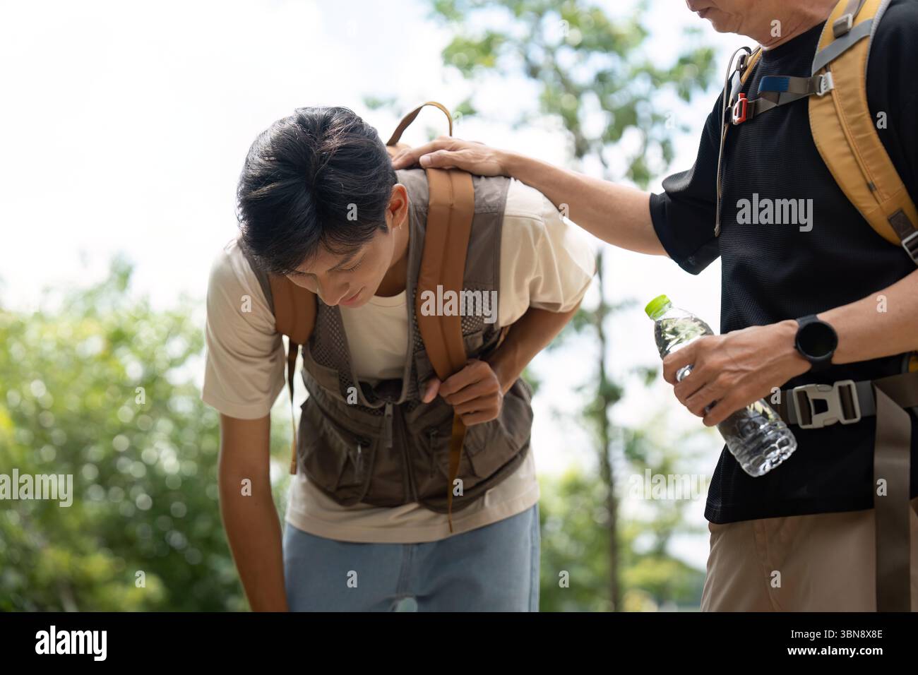 Father Supporting Son on Hiking Trail. A father comforts his son during ...
