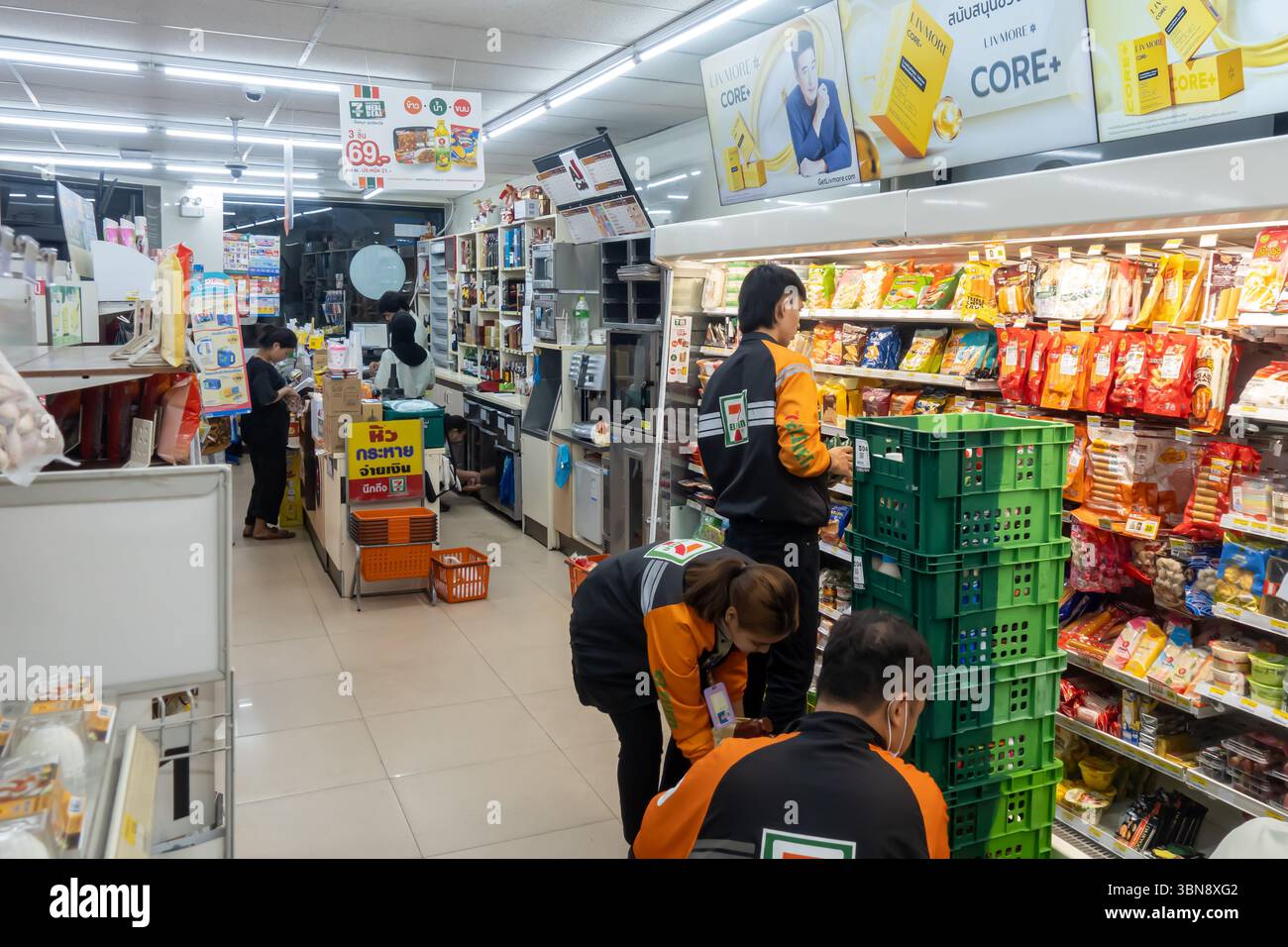 7-eleven staff members sorting out goods on shelves, in 7-11 store in ...