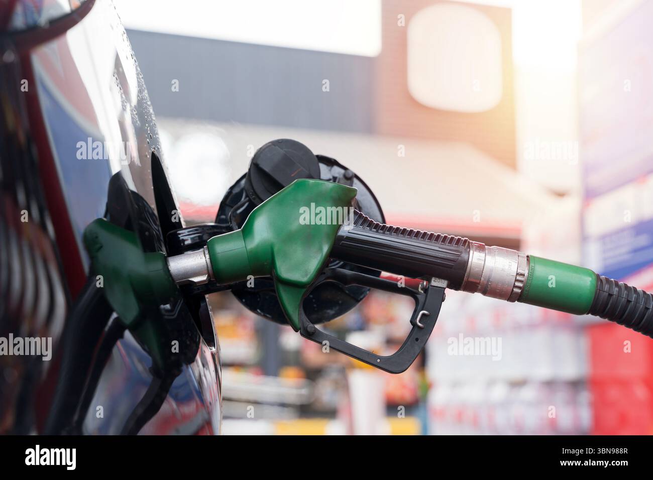 Close-up view of a green fuel pump nozzle inserted into a car’s fuel ...