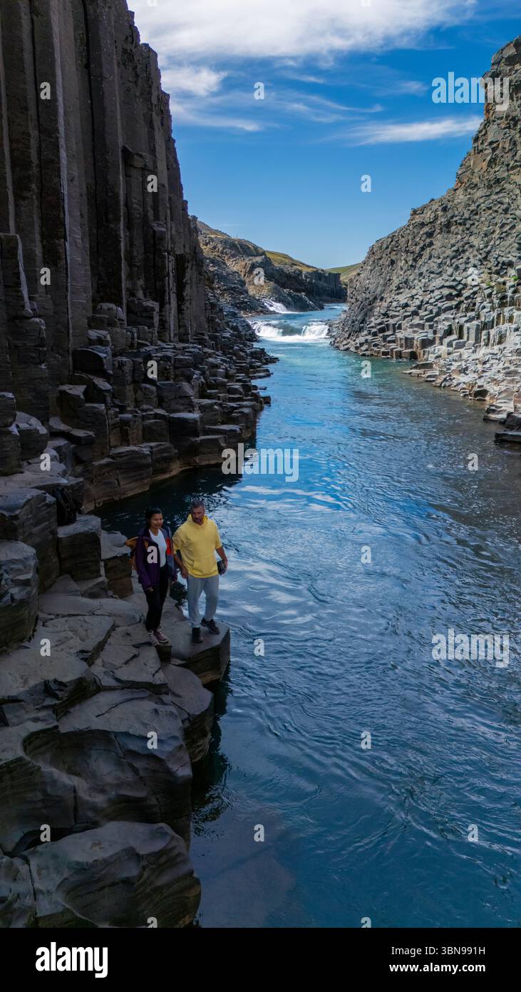 Visitors admire the breathtaking rock formations and turquoise waters of Studlagil Canyon in ...