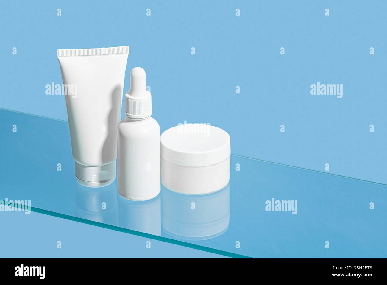 Cosmetic products containers on glass shelf and blue background, copy ...