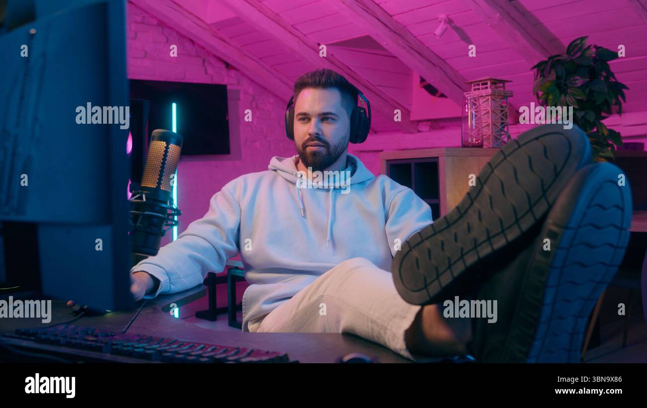 Caucasian guy male gamer man streamer influencer in headphones put legs ...