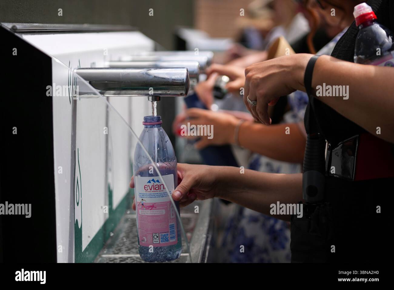 Spectators queue to fill their water bottles during the Wimbledon ...