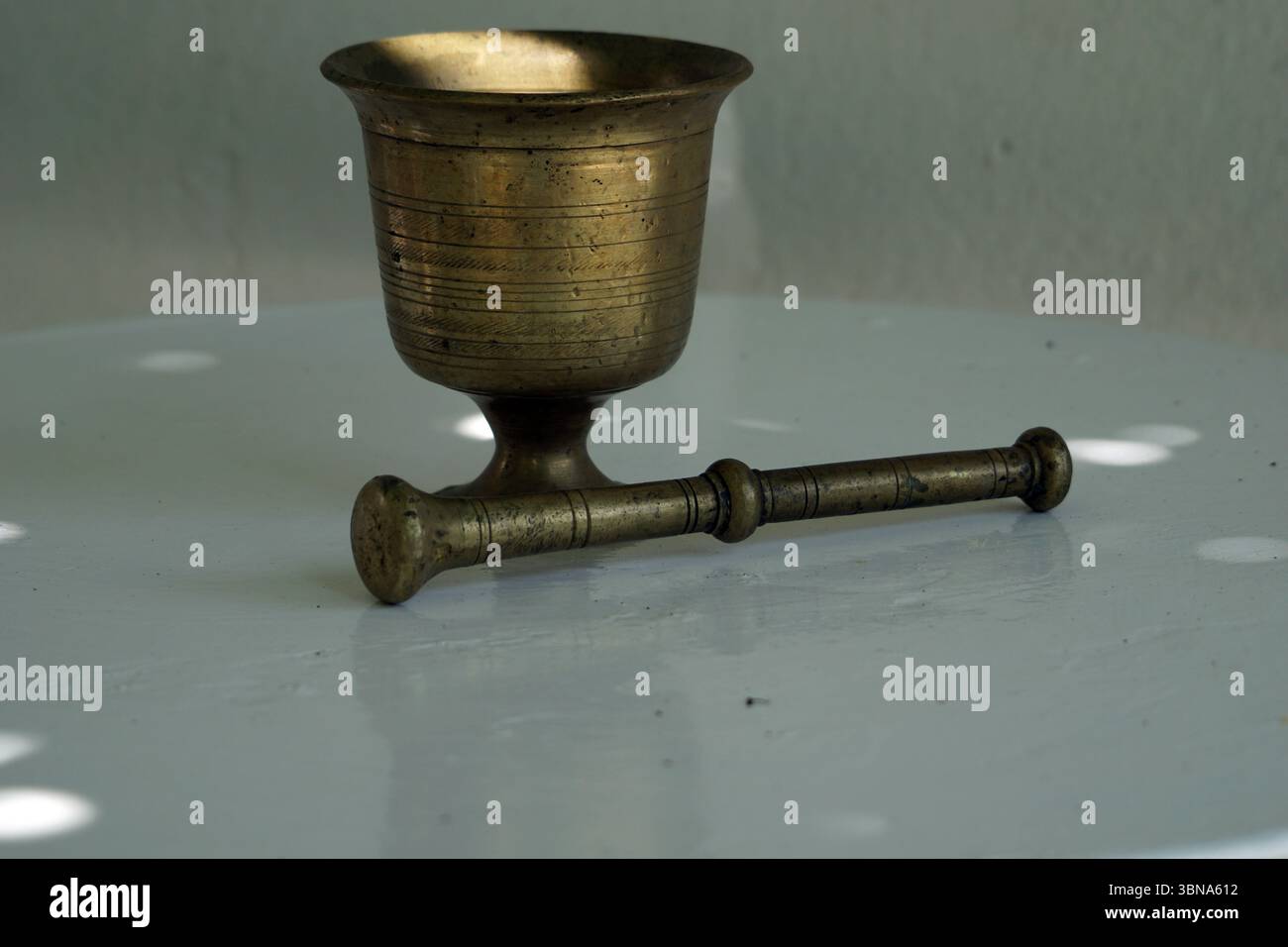 Greek village life, A brass mortar and pestle resting on a white, round ...