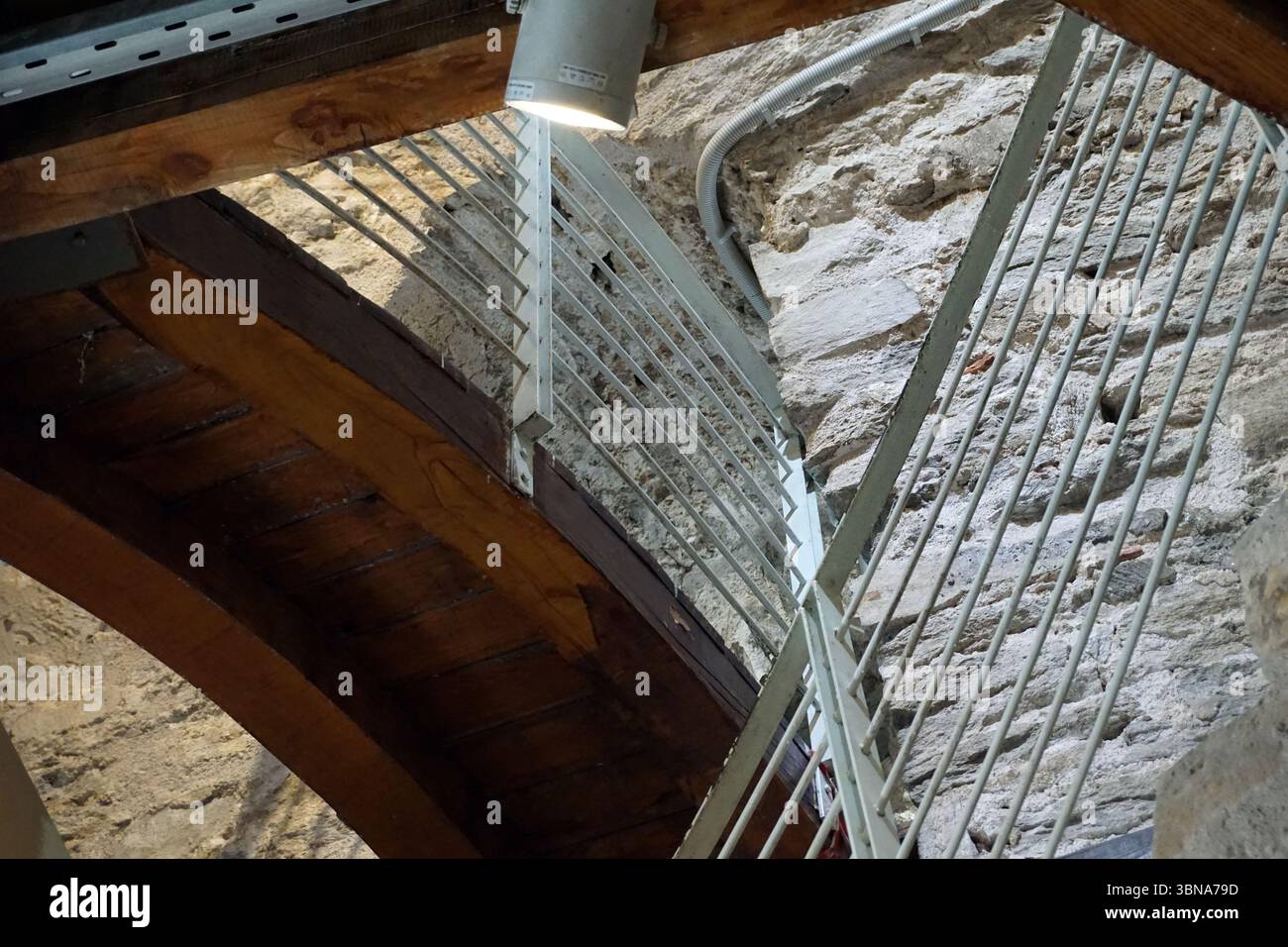 A wooden archway with a metal railing, set within a stone wall. The ...