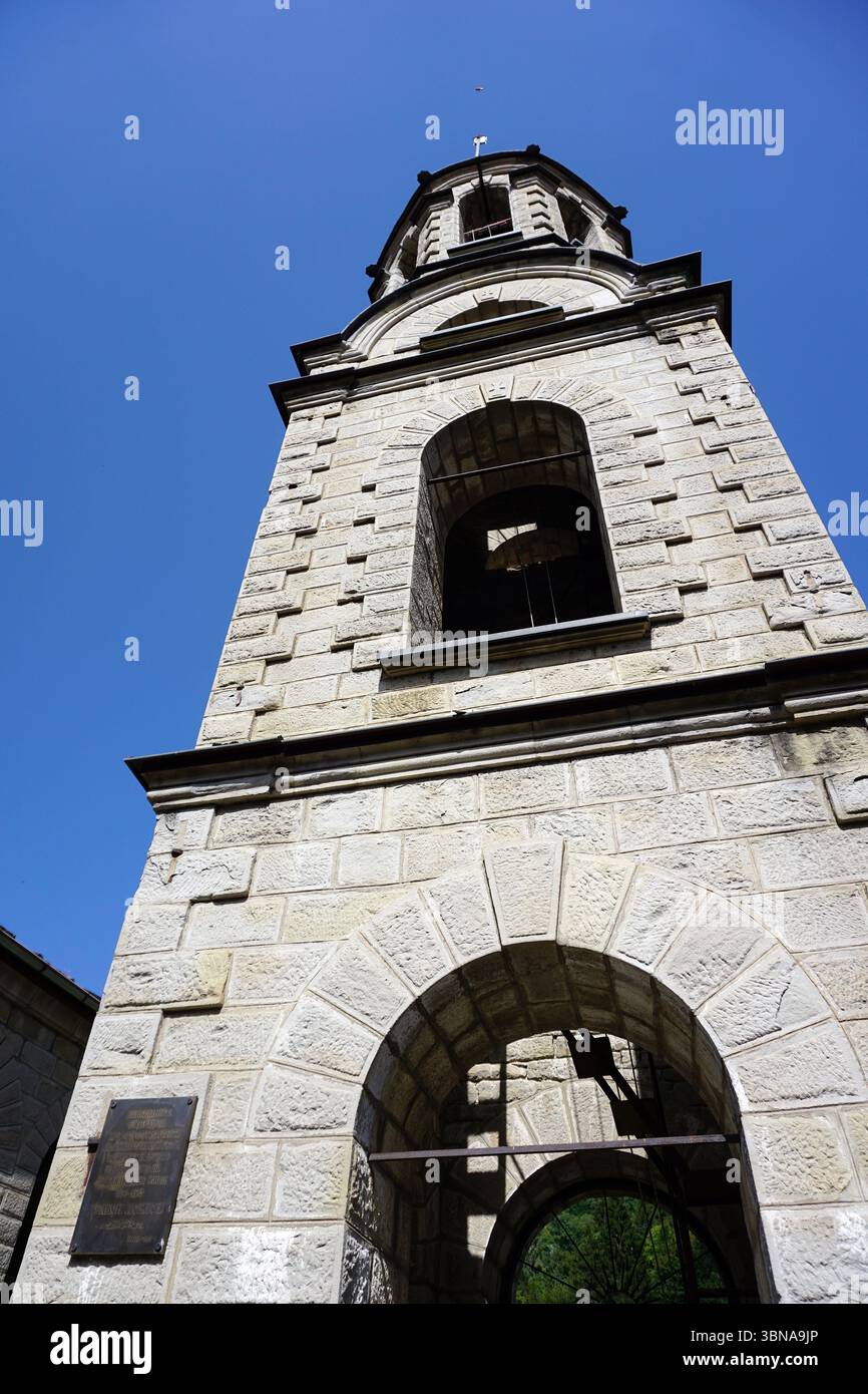 A tall, light beige stone bell tower reaching towards a clear blue sky ...