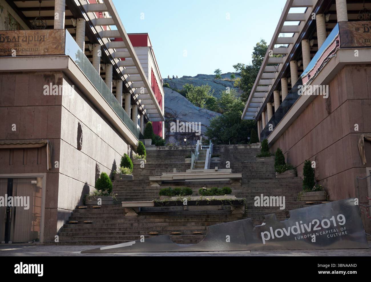 A grand staircase with a metal railing, ascending towards a hillside ...