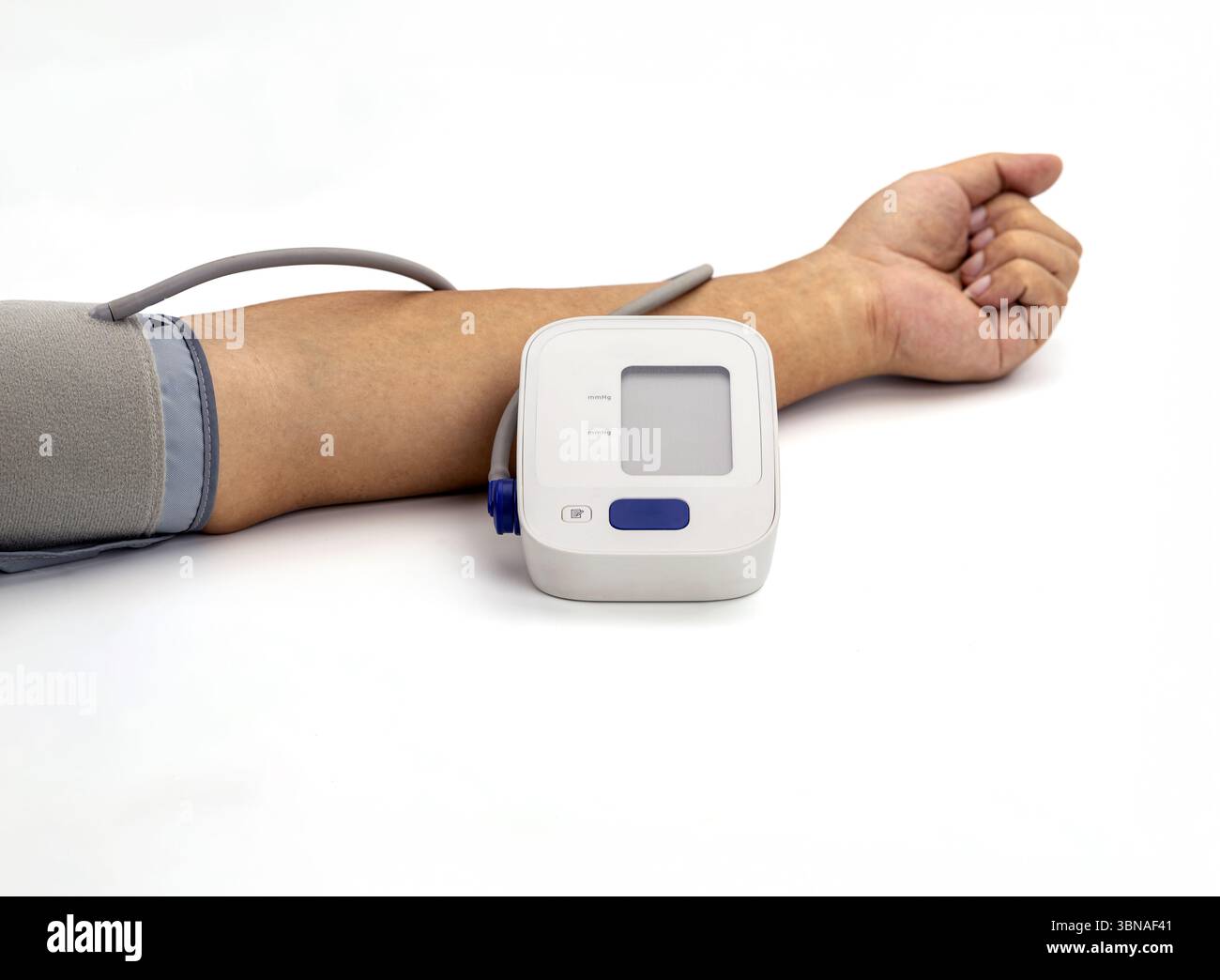 A digital blood pressure monitor is wrapped around arm, displaying ...