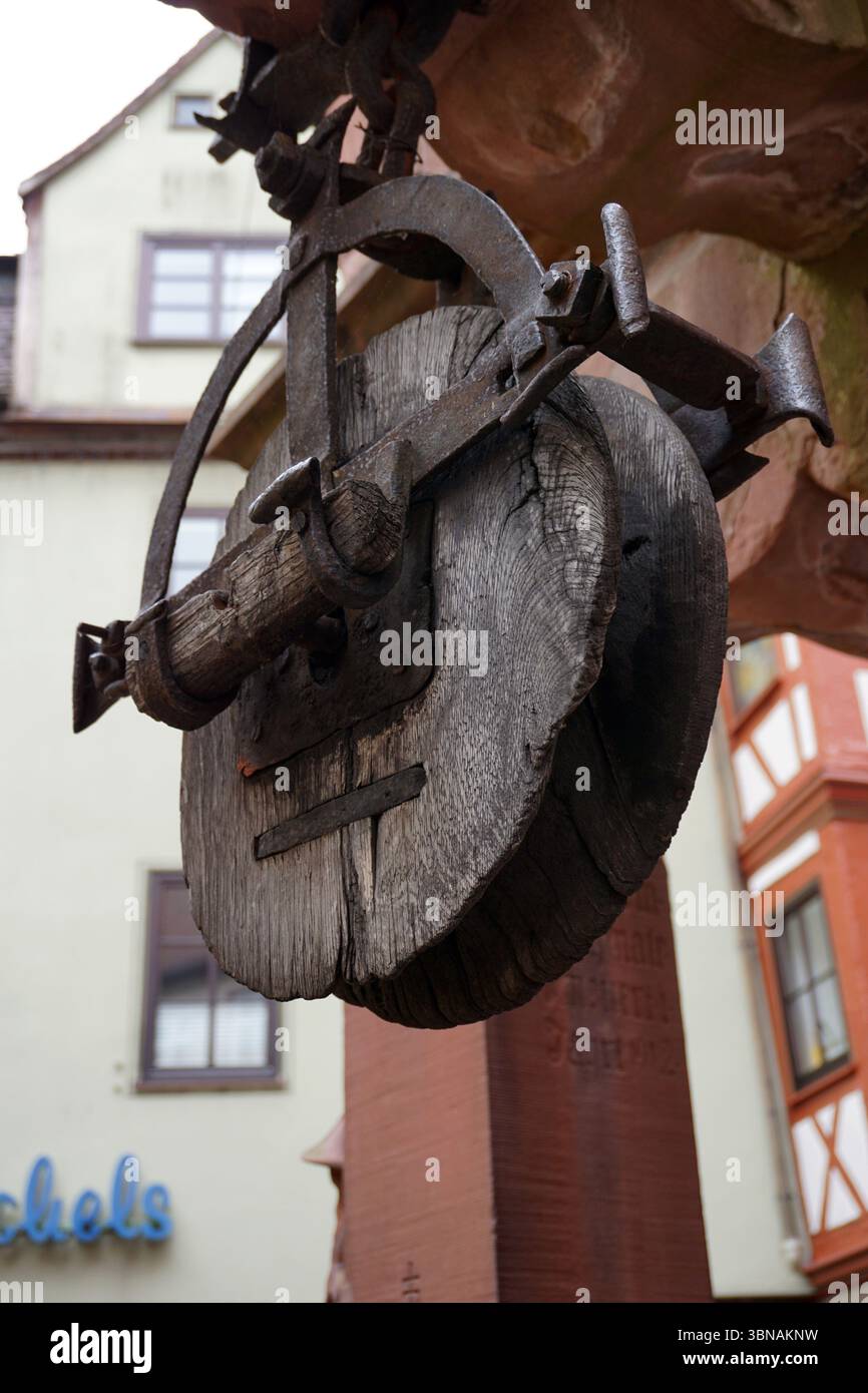 A weathered wooden pulley system suspended from a stone structure. The ...