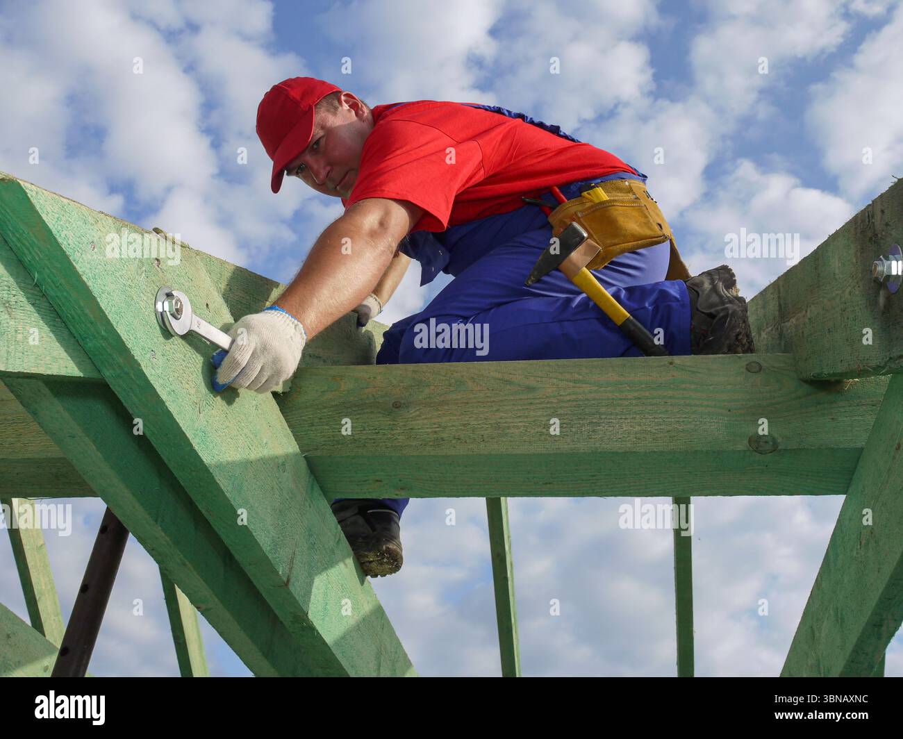 Carpenter tightening bolt connecting rafter and collar beam of house ...