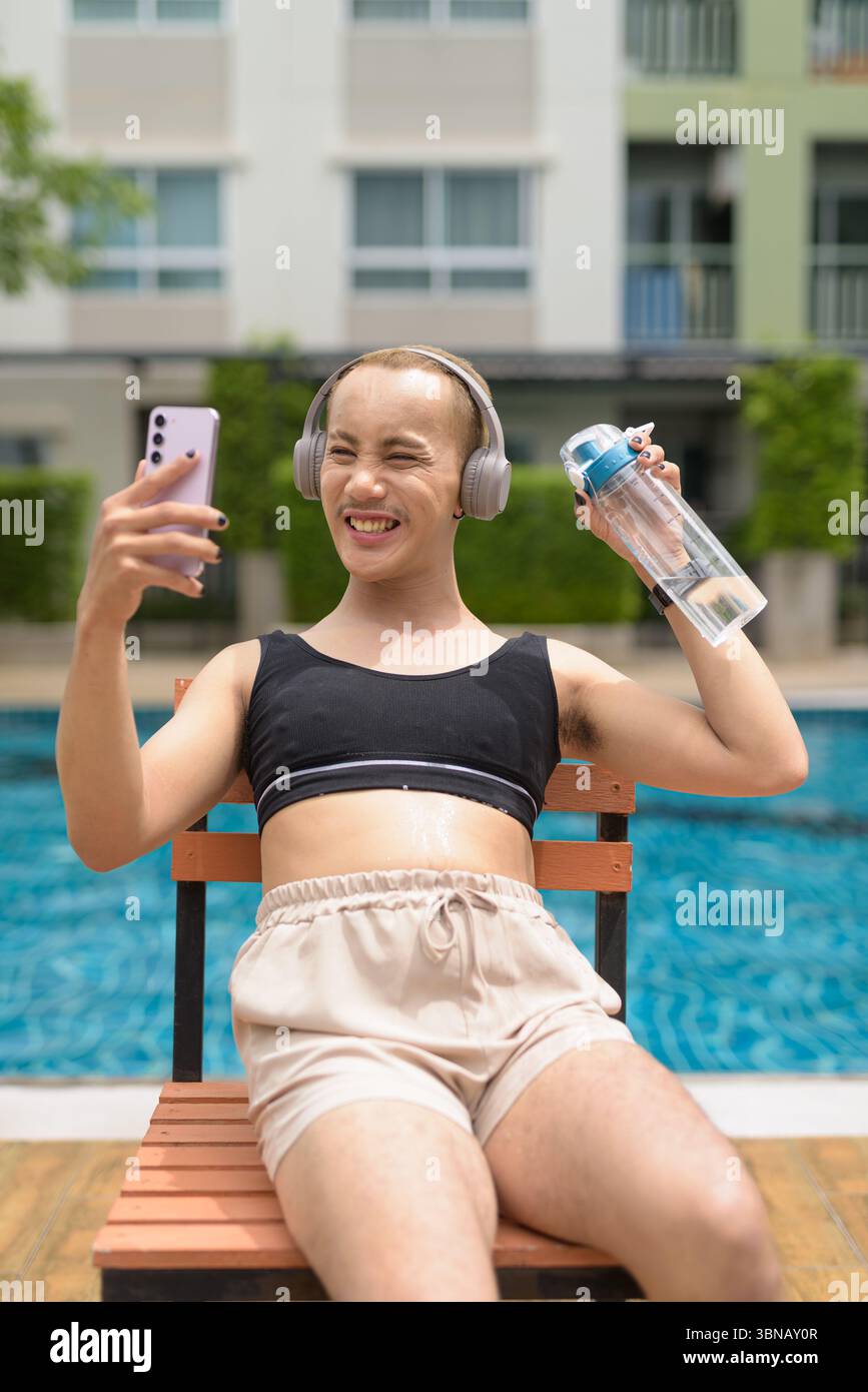 Non-binary Asian person relaxing in poolside during summer wearing sport bra Stock Photo - Alamy