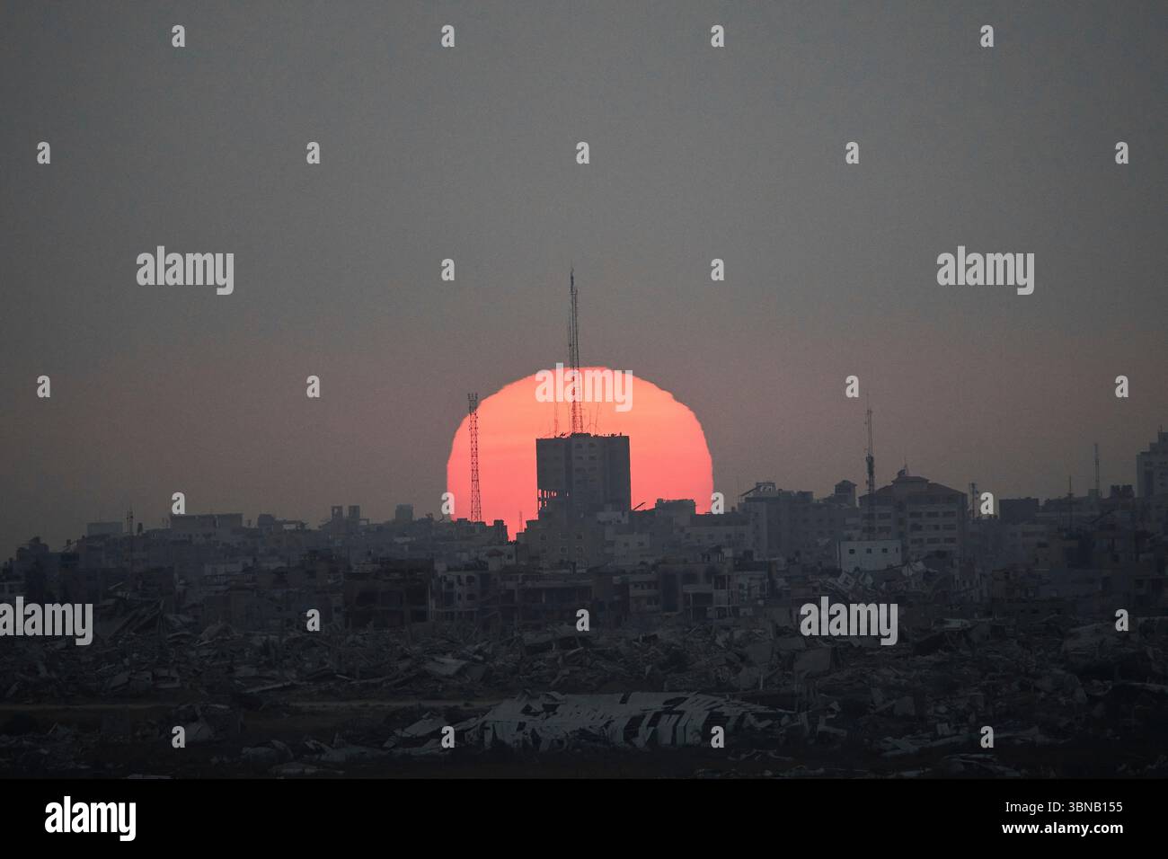 The sun sets over damaged buildings in the Gaza Strip, seen from ...