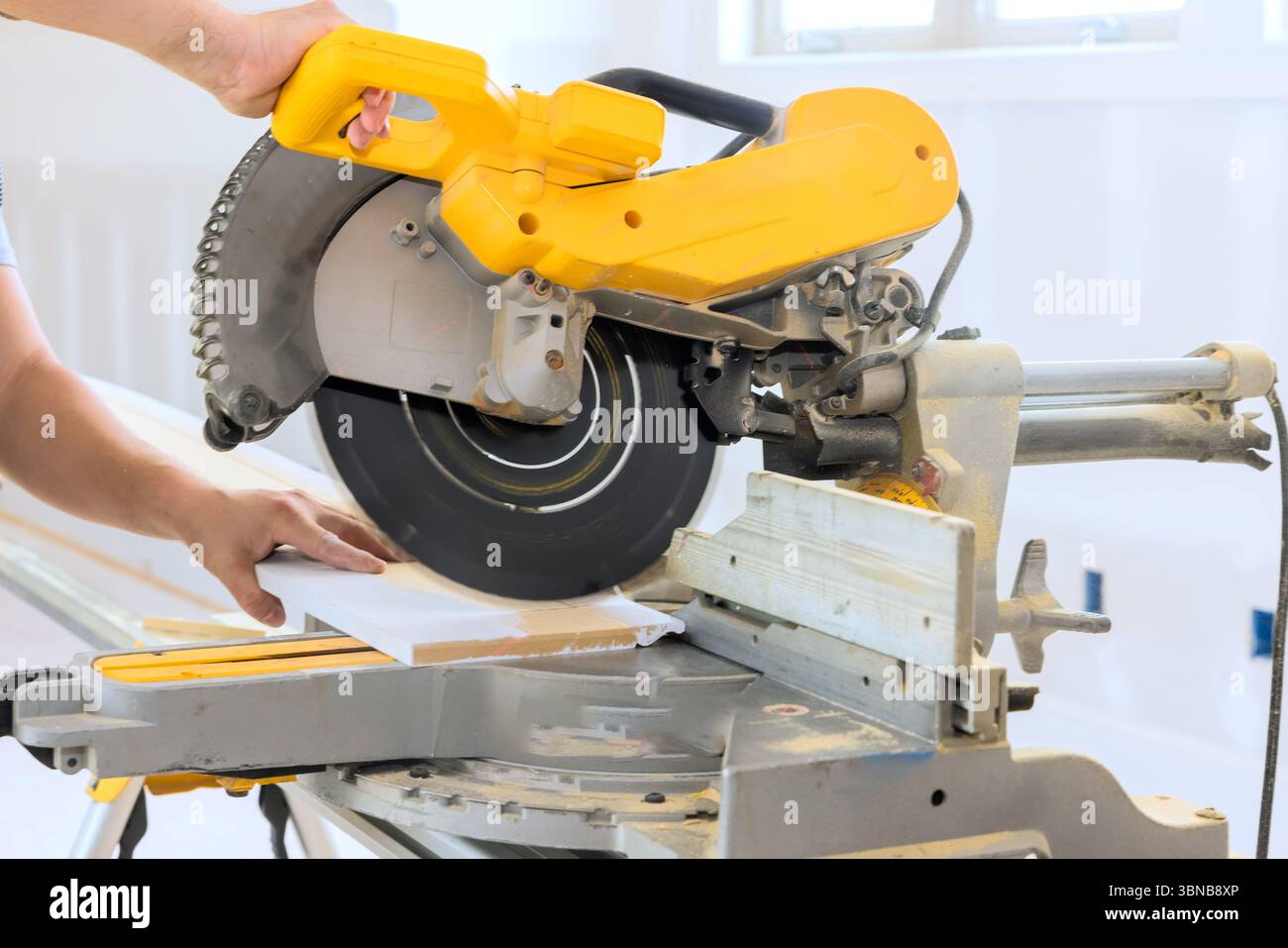 Craftsman operates miter saw to cut wooden materials for project in ...