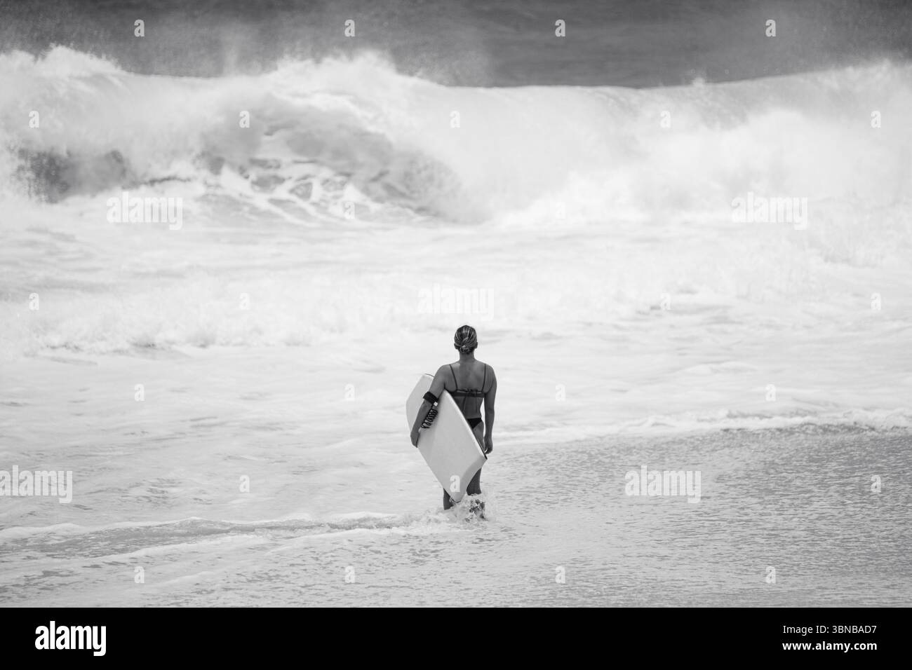 Bodyboarder walks into powerful surf with pink board in hand at a ...