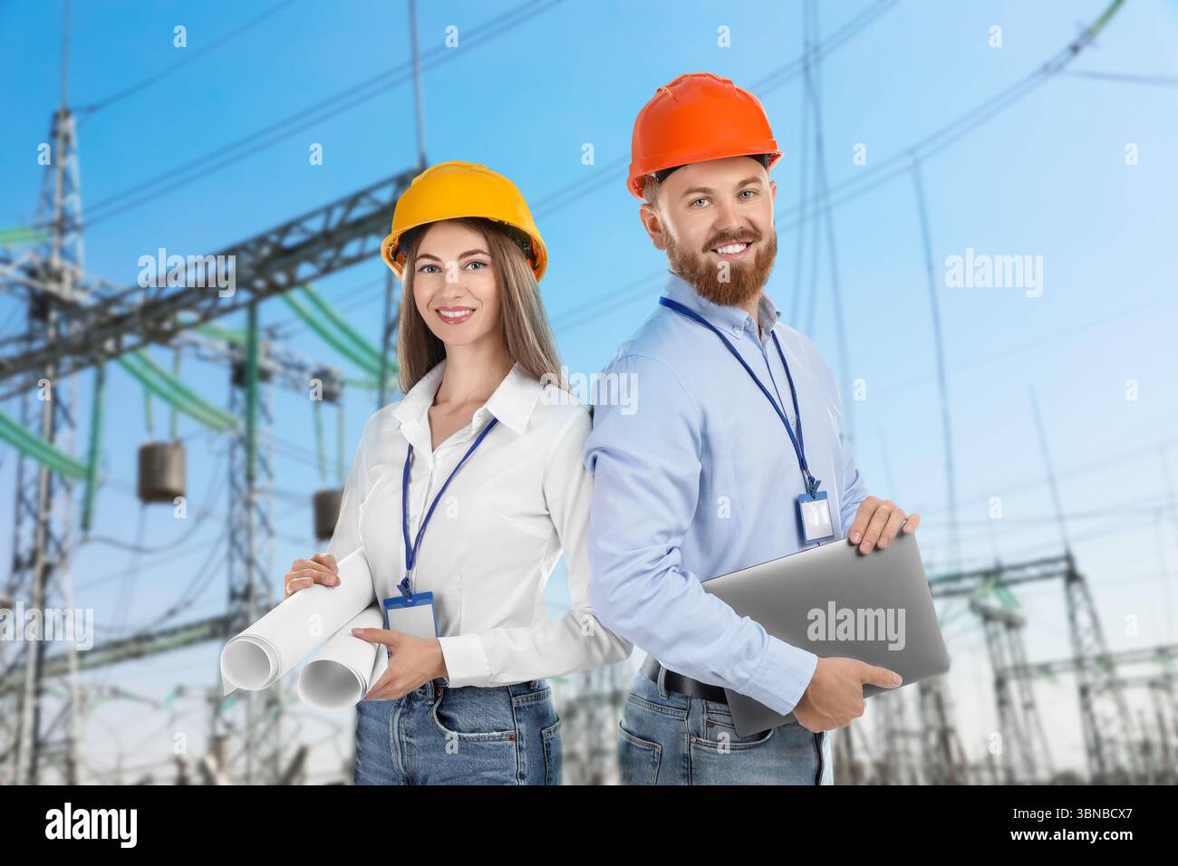 Power engineers in hard hats holding drafts and laptop against ...