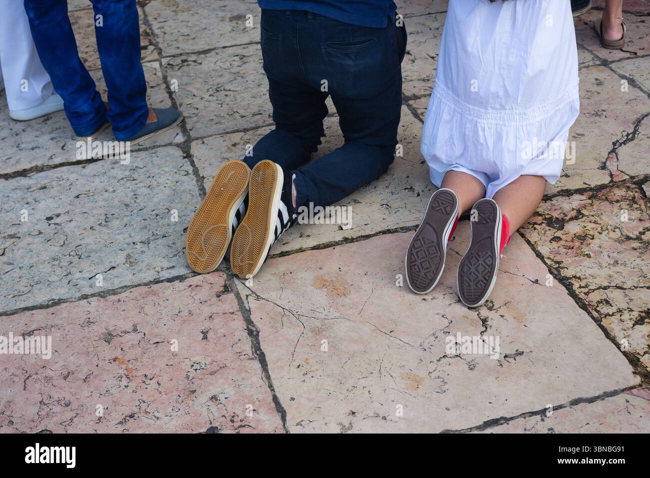 Body part view of people kneeling praying at the door of a church. Legs ...