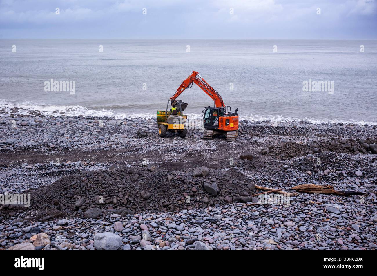 Dredging of rocks using excavator and tipper truck on the shoreline at ...
