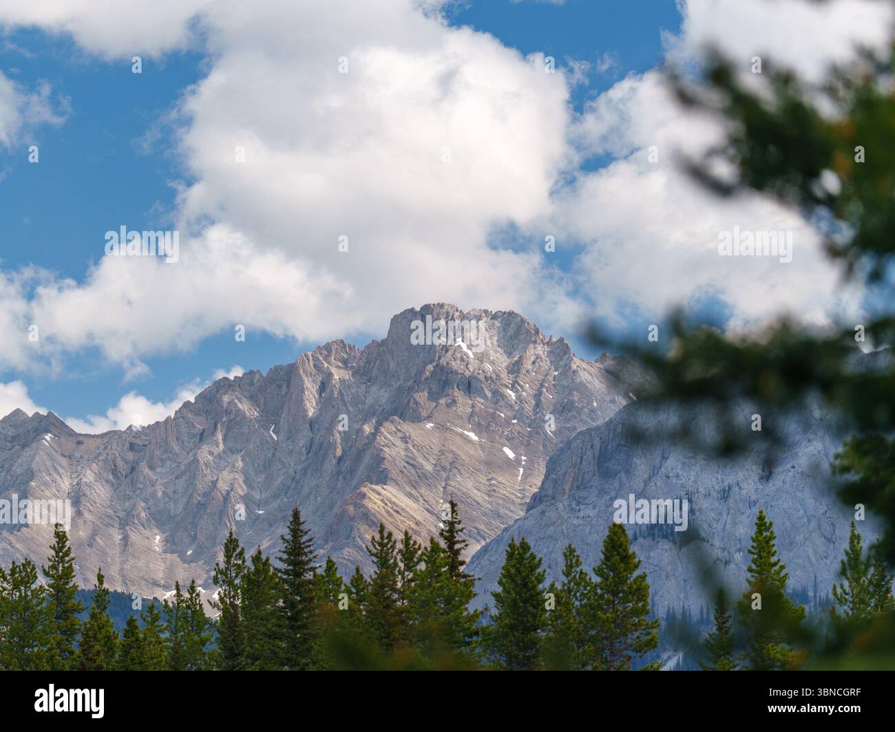 Dramatic rocky mountain peak under a blue sky with scattered clouds ...