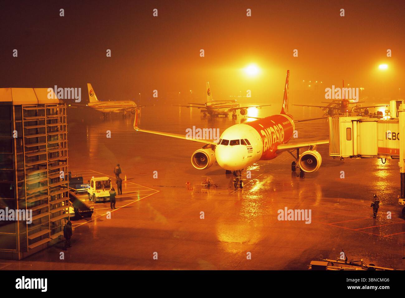 Rain-Soaked Night Apron with AirAsia A320 under Sodium Floodlights ...