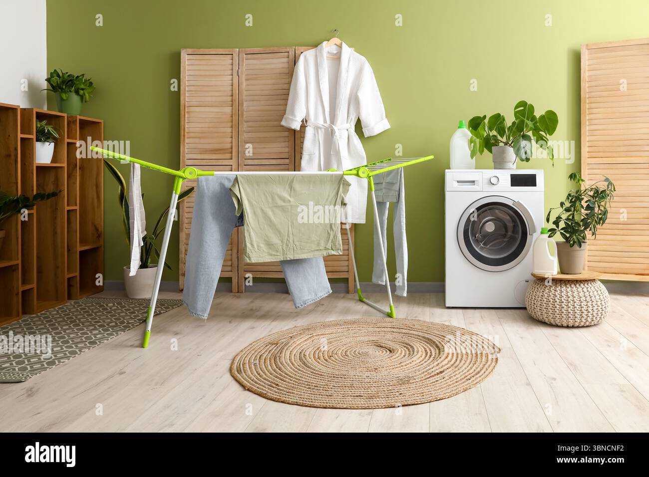 Laundry room interior with washing machine and clothes on drying rack ...
