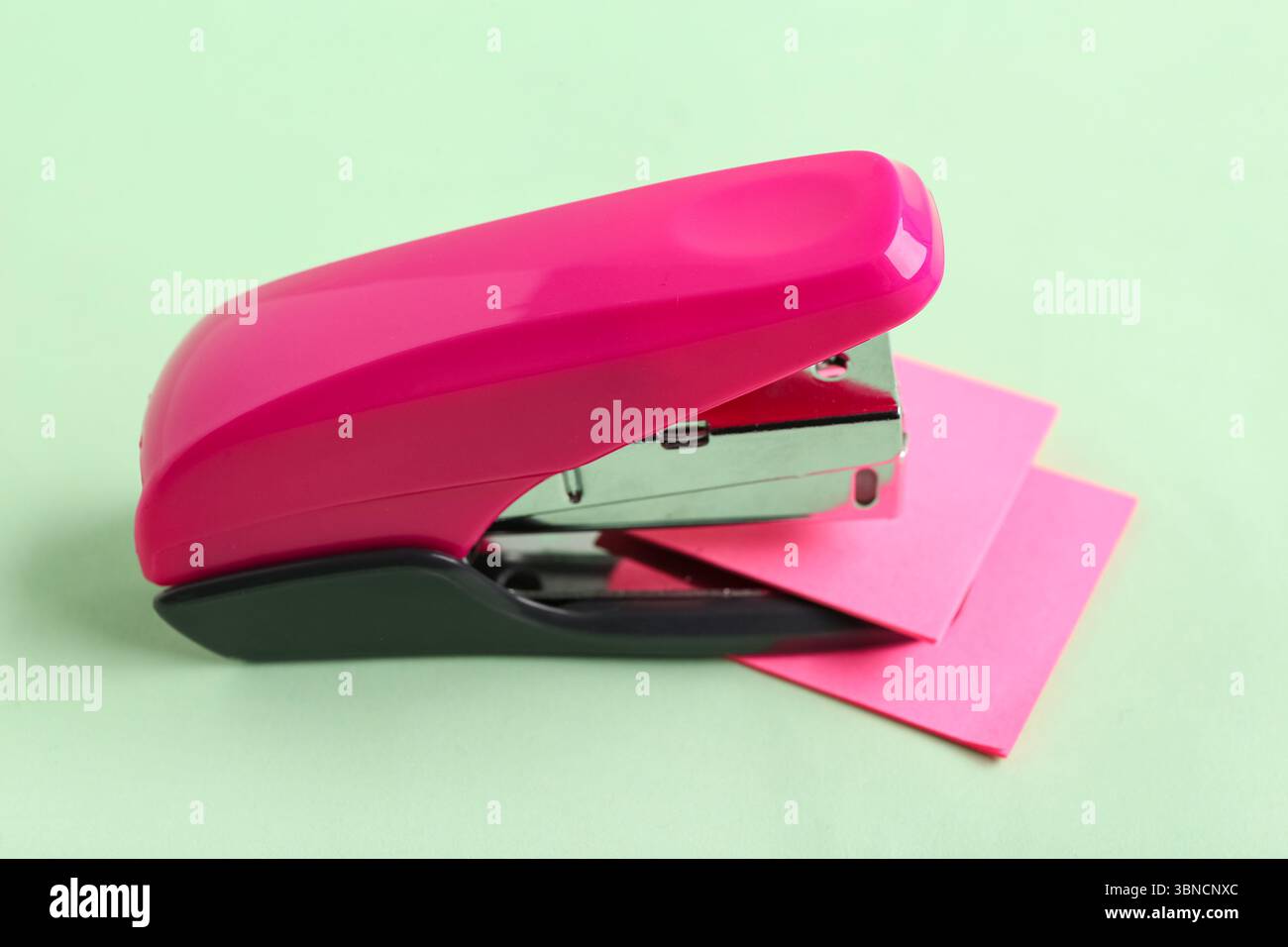 Pink stapler with sticky notes on green background Stock Photo - Alamy