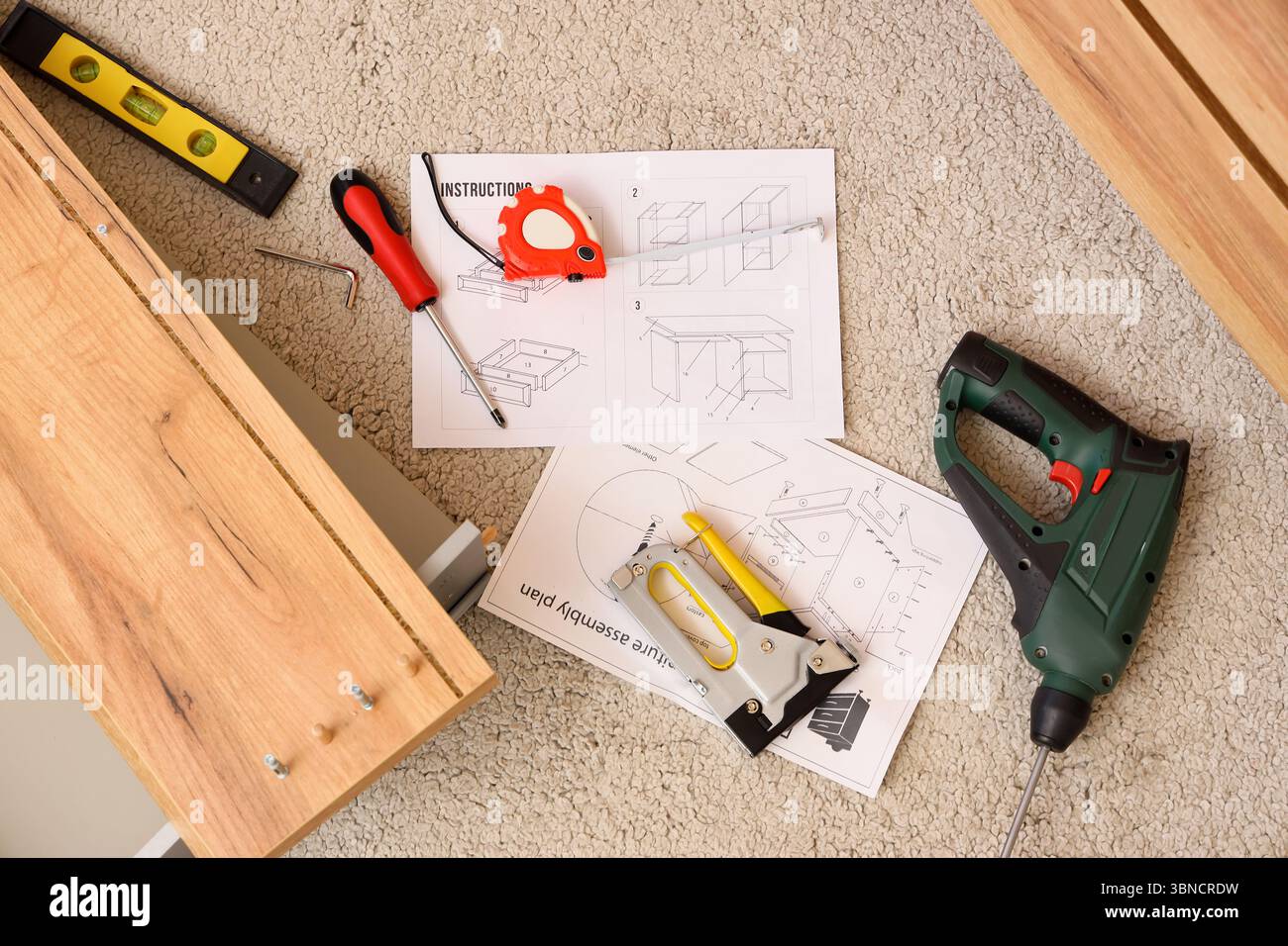 Disassembled chest of drawers with tools and instructions on carpet ...