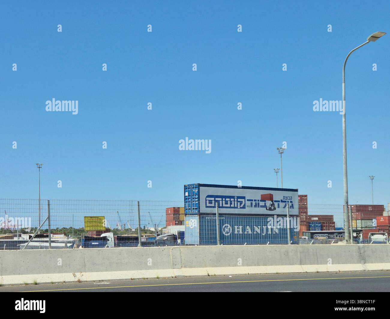 A fenced shipping yard with stacked containers and cranes in the ...