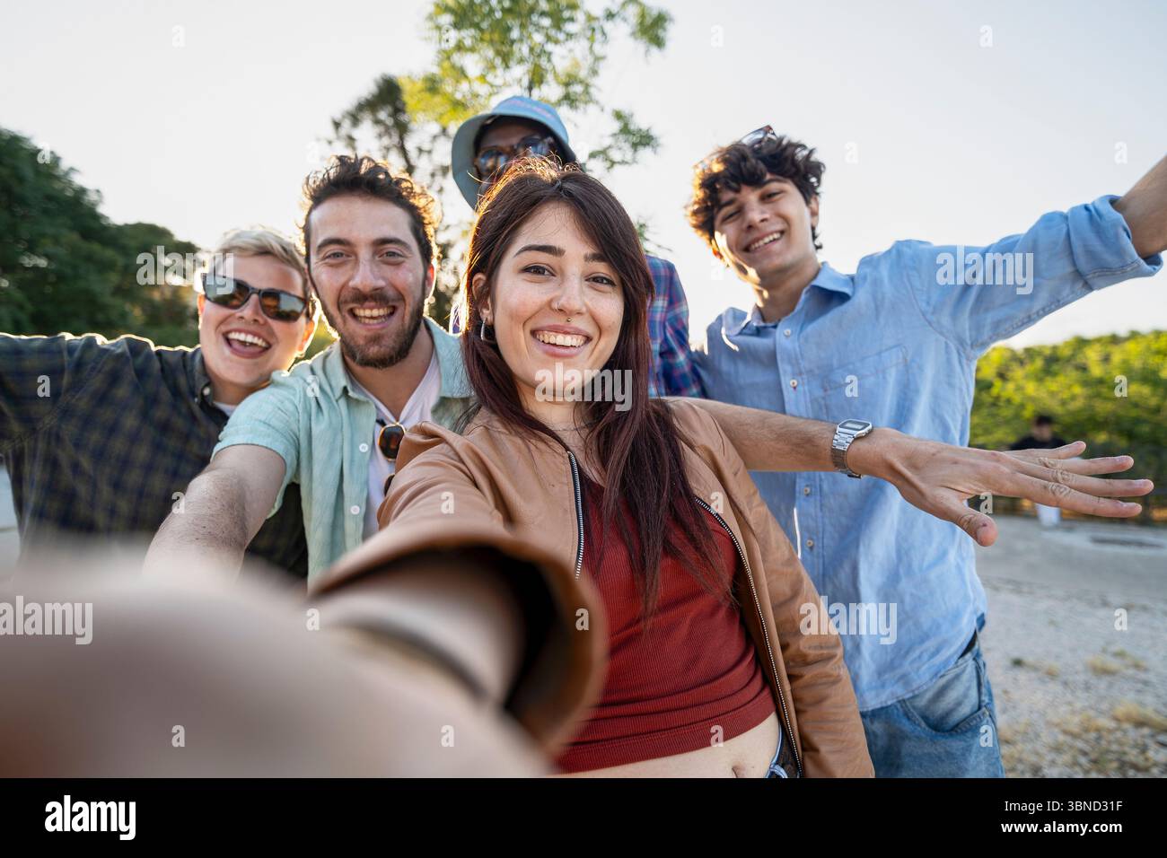 Smiling Gen-Z friends making fun selfie on a sunny adventure, arms ...