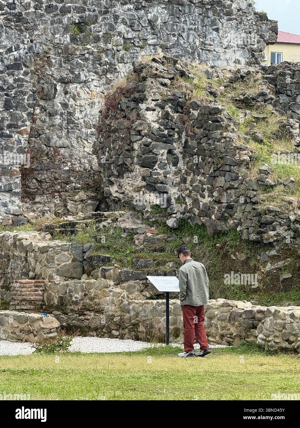 This image shows a man reading an informational sign at an ...