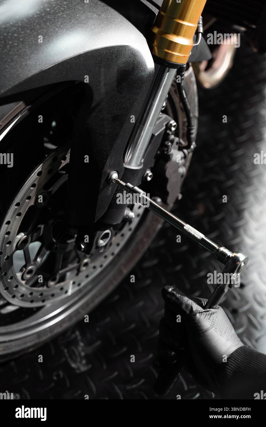 Mechanic performs front suspension service on motorcycle, adjusting ...