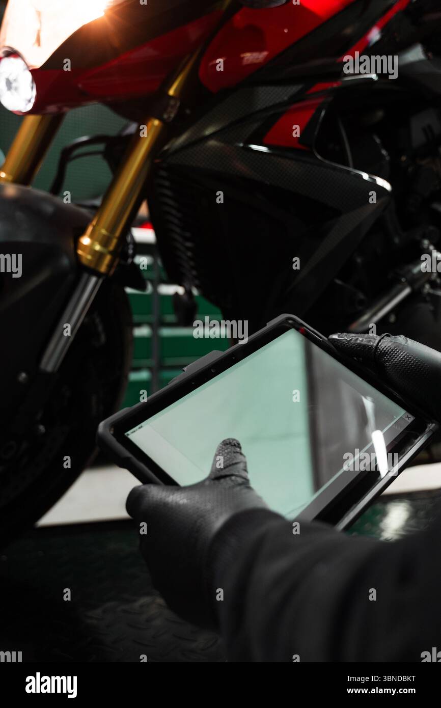 Mechanic performing system diagnostics via tablet. Motorcycle system ...