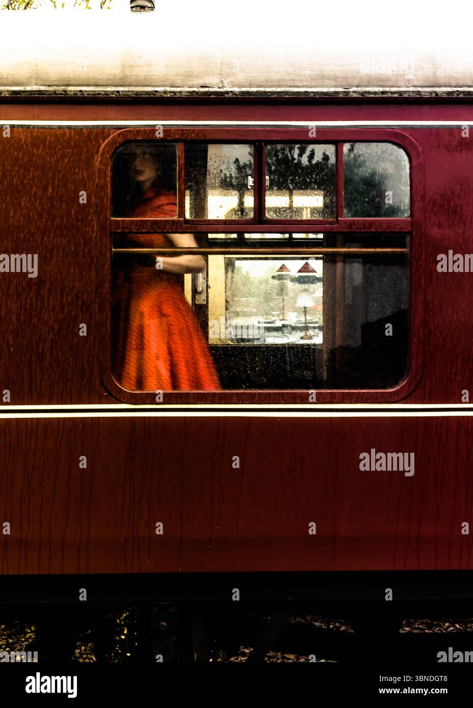 A woman in a red dress stands inside a train car, looking out the ...