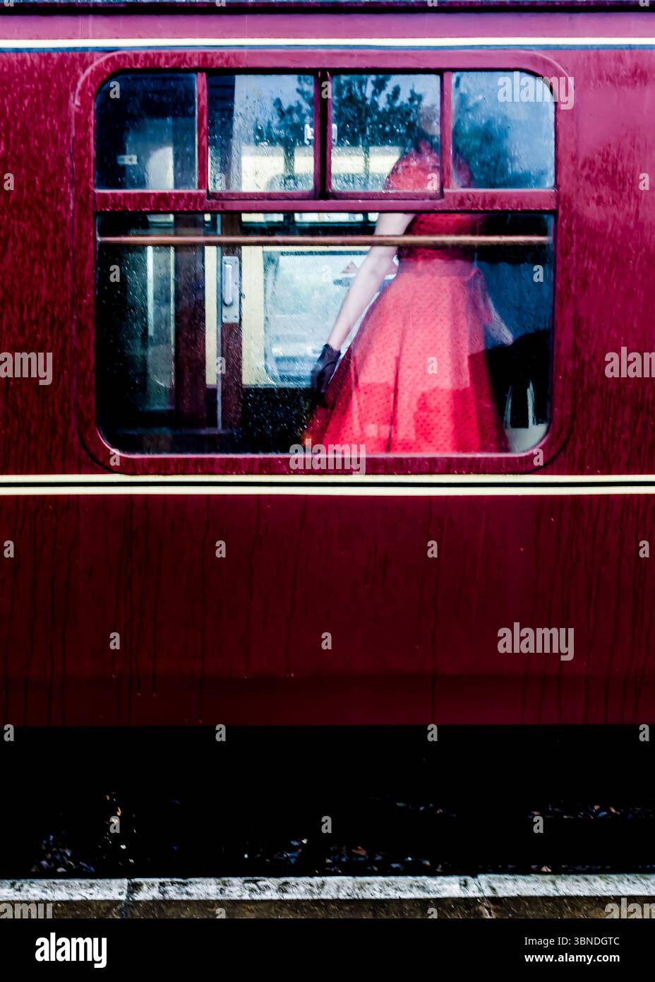 A woman in a red dress and black gloves is seen through the window of a ...