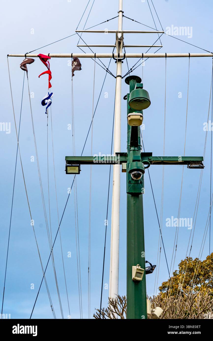 A modern light and surveillance camera tower stands beside a replica ...
