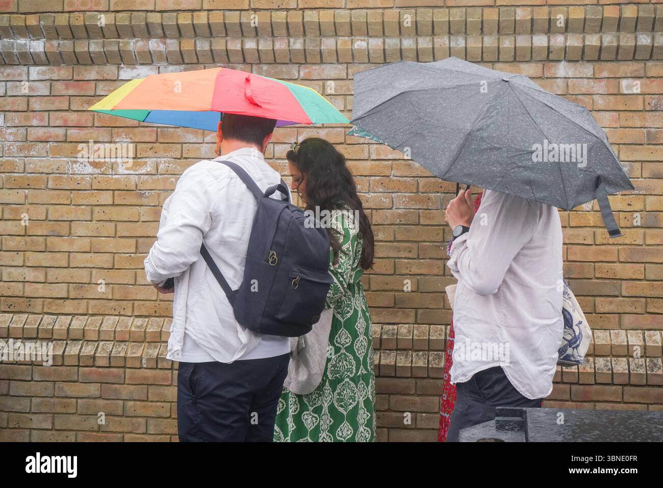 London, UK. 2 July 2025. Tennis spectators shelter with umbrellas as ...