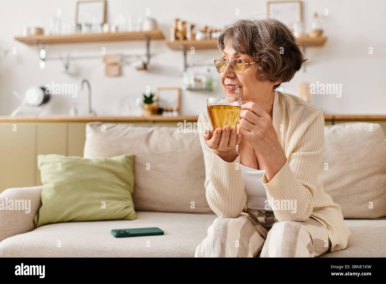 Senior woman enjoys a warm beverage while relaxing comfortably at home ...