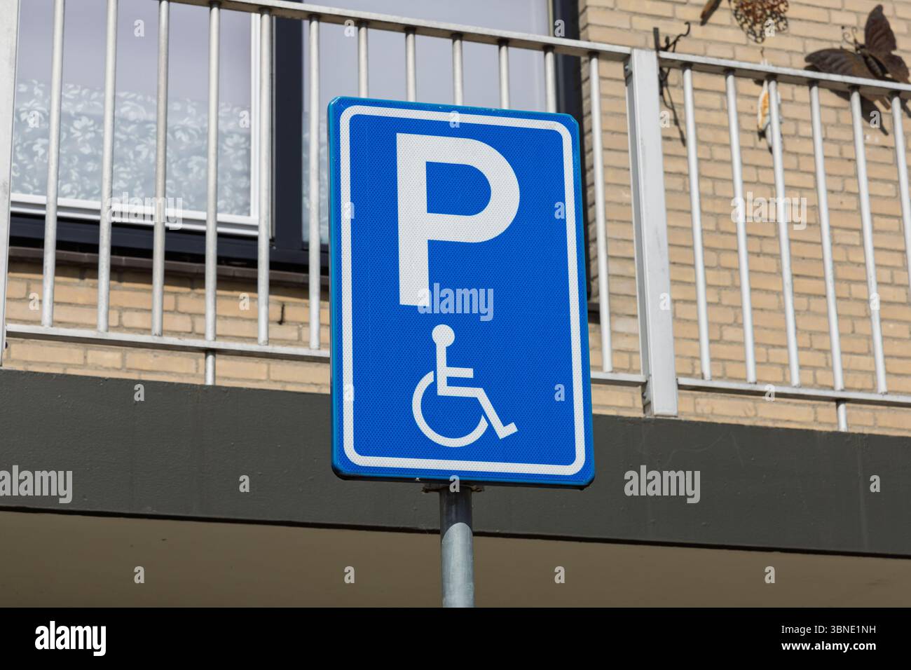 A prominent blue sign indicates disabled parking, featuring the ...