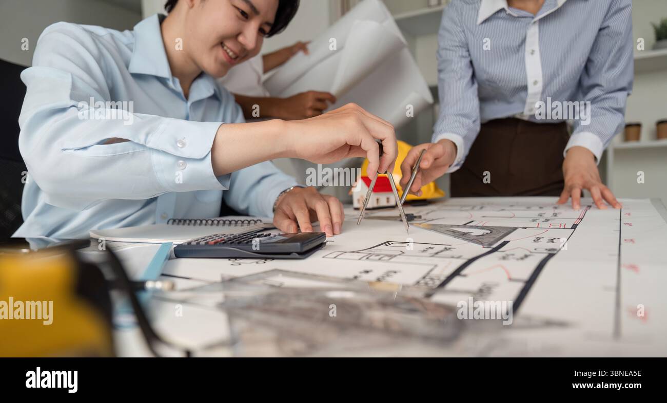 Teamwork and Blueprint Analysis. A focused architect using a compass to ...